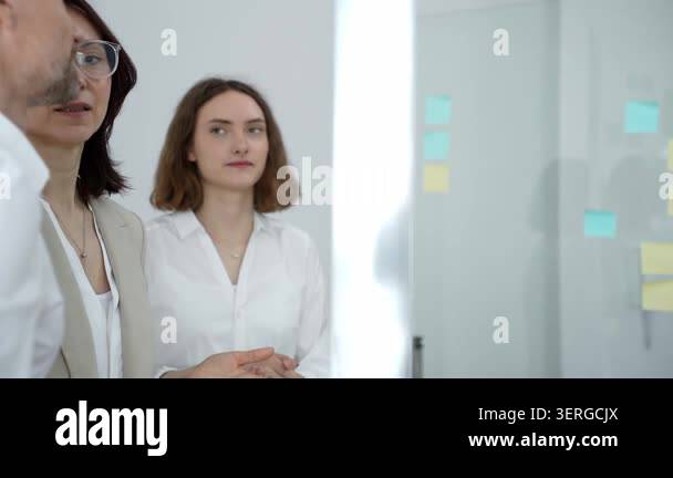 Business colleagues brainstorming at a bright modern office, writing on ...