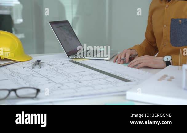 Architect working on construction plans using a laptop, drafting new ...
