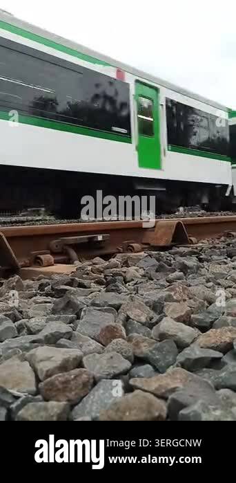 A low-angle close-up view of a passenger train moving on railway tracks ...