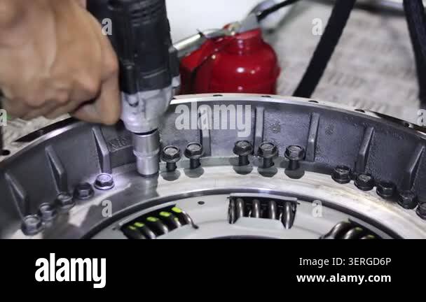 A close-up of a mechanic using an electric impact wrench to tighten ...