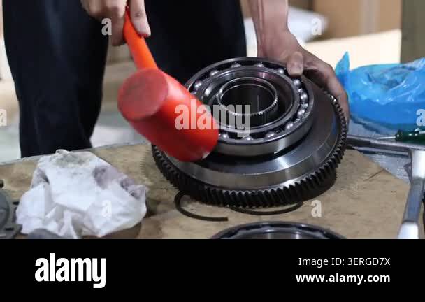 A close-up of a mechanic using a mallet to carefully assemble a large ...
