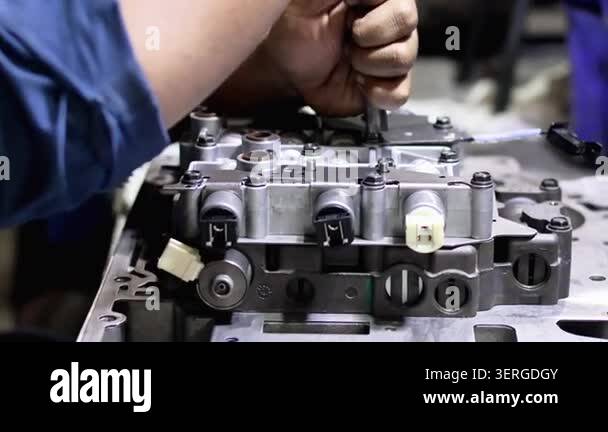 A close-up of a mechanic using a hand tool to service an automatic ...