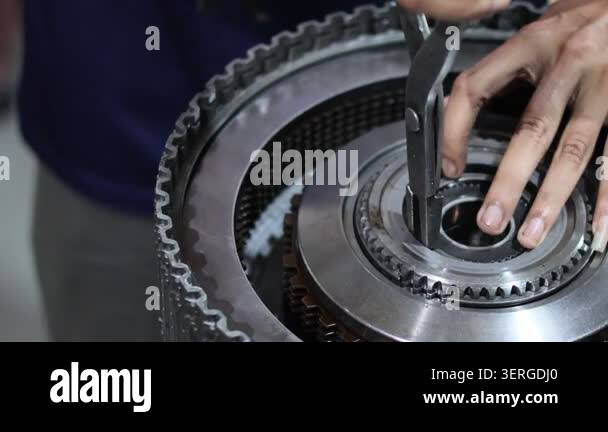 A mechanic uses snap ring pliers to assemble or repair an automatic ...