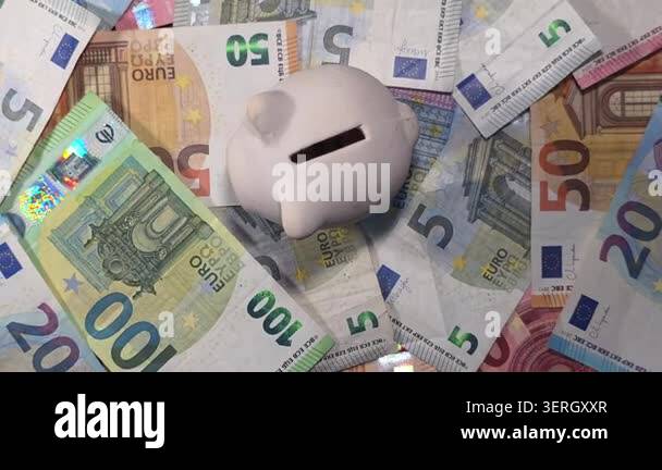 Close-up top view of a white ceramic piggy bank on a rotating collage ...