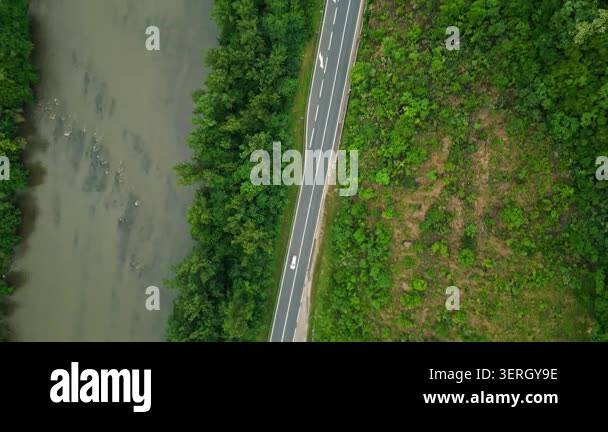 Drone shot of a winding river and empty highway running through a green ...