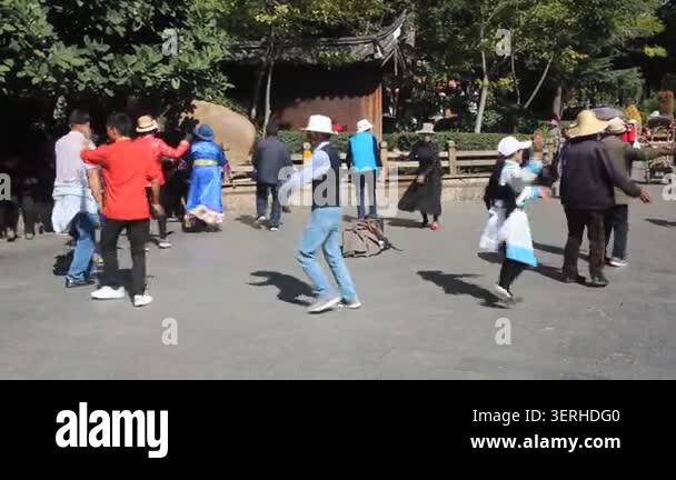 Group of people dancing in a circle outdoors in a park with trees and ...