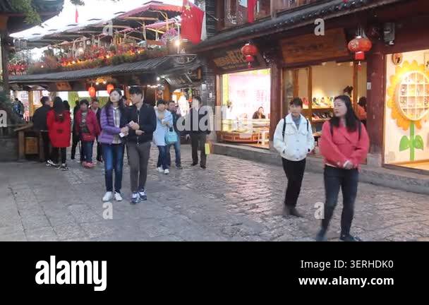 People walking on cobblestone street in front of shops and restaurants ...
