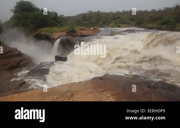 Powerful waterfall cascades over rocks with white foamy water and mist ...