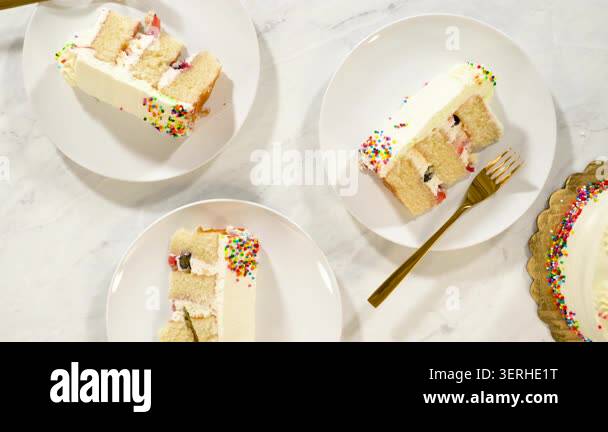 Three white dessert plates with neatly sliced pieces of vanilla cake ...