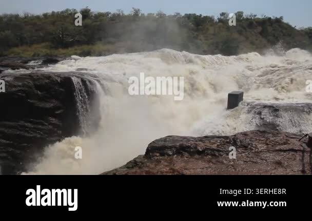 Powerful waterfall cascades over rocks with white foamy water and mist ...