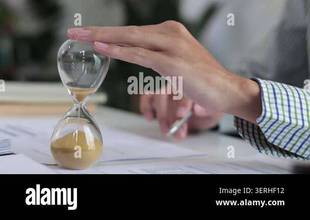 Close up of hand on running sandglass for deadline and time management ...