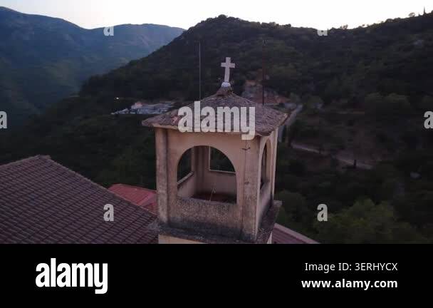 An Orthodox church bell tower with marble cross rises above a mountain ...