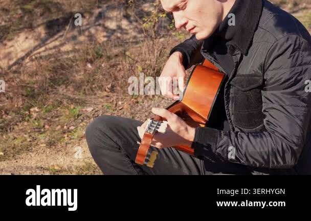 Close up hands of playing string guitar outdoors in autumn forest ...