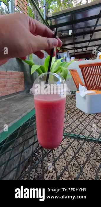 Video of Hand stirring pink Guava smoothie with black straw. Metal ...
