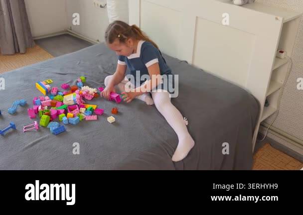 Preschooler girl plays with bright plastic cubes, exploring textures ...