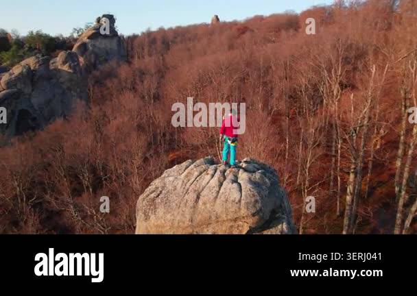 Rock climber pauses on top of boulder in evening light, overlooking ...