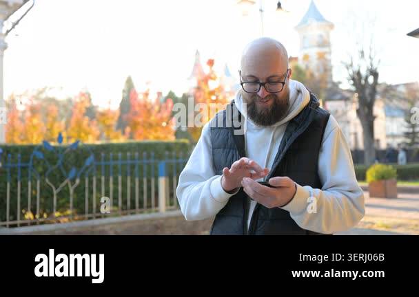 Man enjoys beautiful autumn day in park, engaging with smartphone under ...