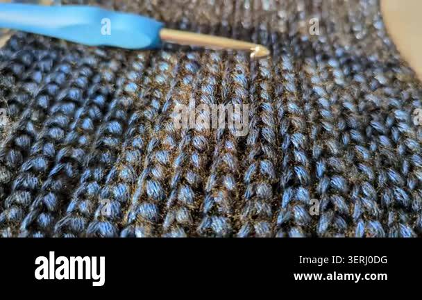 Crochet hook on handmade warm textured, shiny dark blue fabric ...