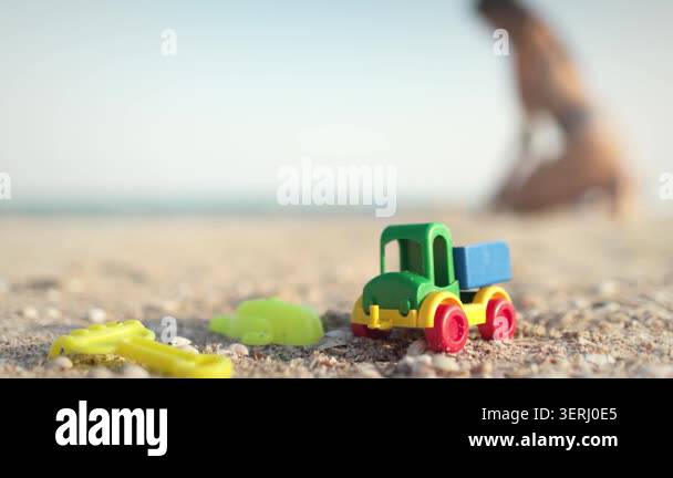 Many bright multi-colored plastic toys lie on a large sea sandy beach ...