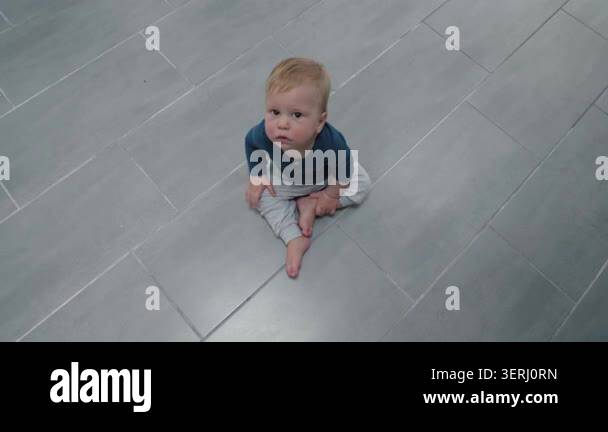 Child sitting on tiled floor. Dreaming little boy looking at camera ...