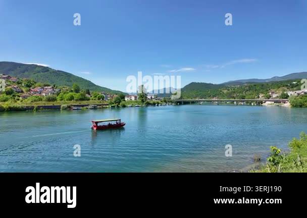 Small boat floating on the calm Drina River surrounded by mountains and ...