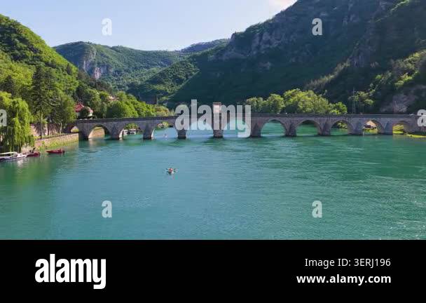 Wide drone shot of Mehmed Pasha Sokolovic Bridge with kayakers on the ...