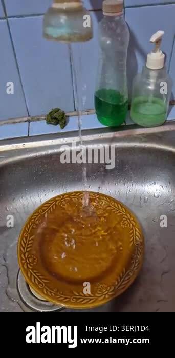 Vertical overhead close up of clear water flowing from a faucet into a ...
