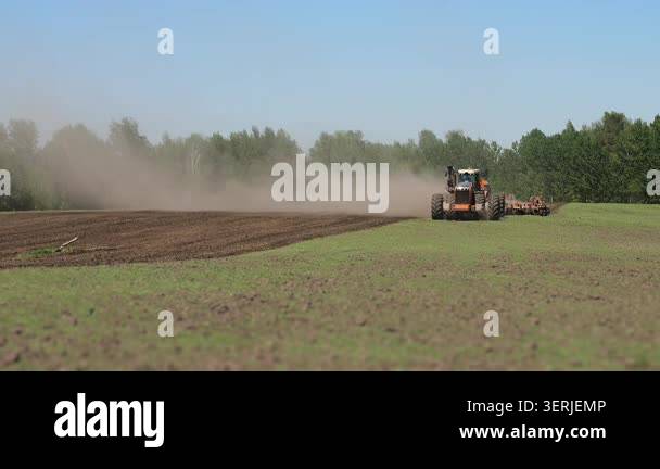 Modern agricultural tractor cultivating farmland and preparing soil for ...