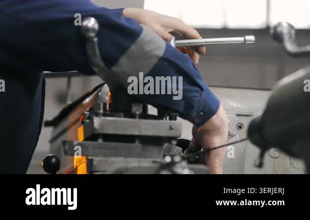 Skilled machinist adjusting industrial lathe machine in manufacturing ...