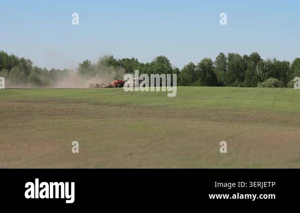 Tractor with pneumatic seeder planting crops across agricultural field ...