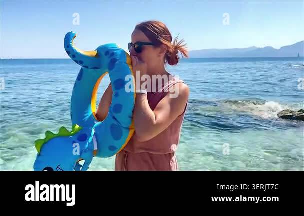 Woman inflating swim ring at sea beach.mom preparing float ring for ...
