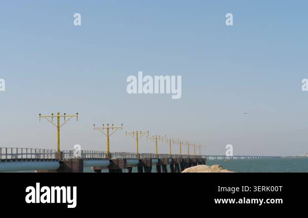 Airport runway approach light towers on a sea pier under a clear blue ...