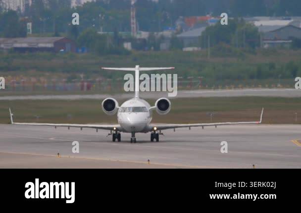 Regional jet airplane taxiing on airport runway during daytime with ...