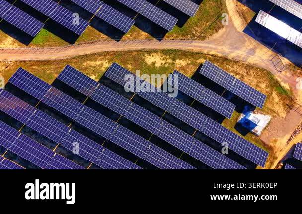Solar panels beside curved gravel road on hillside. Top-down drone view ...