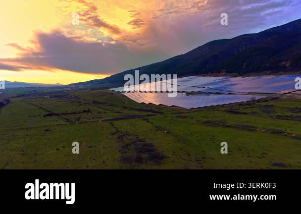 Sunset light over solar farm and green valley, Bulgaria. Elevated drone ...