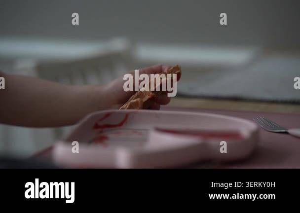 Toddler hand holding a piece of baked waffle and dipping it into red ...