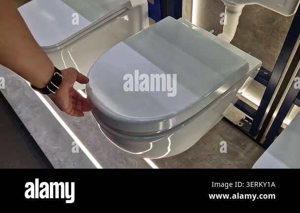 A man's hand lifts the lid of a modern wall-hung toilet. Choosing a ...