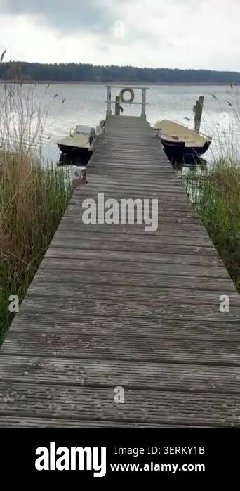Wooden pier extending into calm lagoon waters on Rugen Island, Germany ...