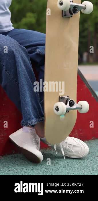 Close-up of legs in white sneakers and skateboard. Young woman in blue ...