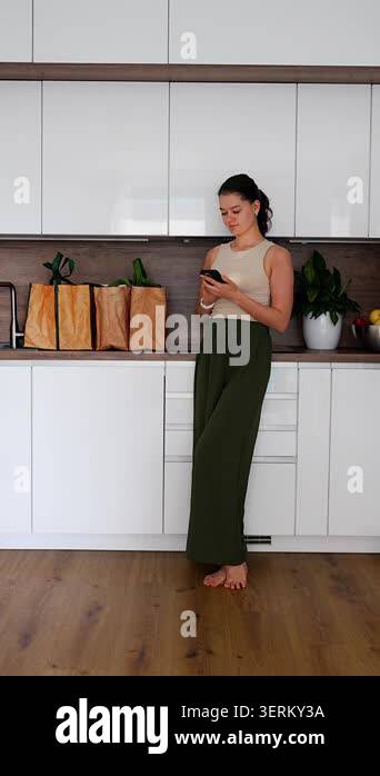 Woman checking grocery delivery with smartphone while unpacking ...
