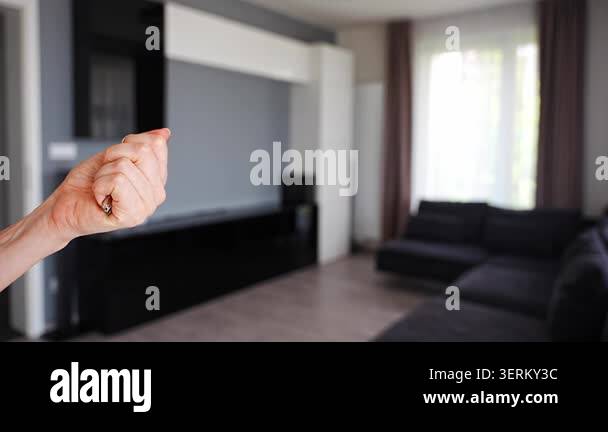 Hand holding apartment keys in furnished resale apartment living room ...