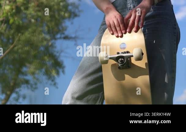 Young girl in white t-shirt and jeans holding skateboard against blue ...