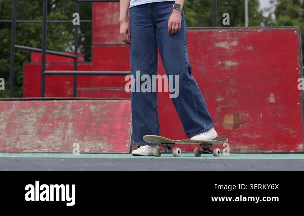 Unrecognizable person in wide jeans and white sneakers on skateboard in ...