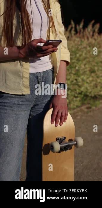 Young girl with a skateboard and a smartphone in her hands. Concept of ...