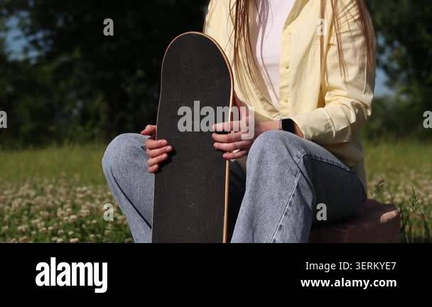 Close-up of girl's hands holding skateboard. Young teenage girl with ...