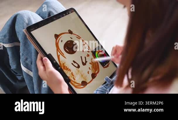 Child wearing pink cap drawing cute cartoon capybara on digital tablet ...