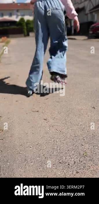 Generation Alpha girl riding inline roller skates on asphalt street ...