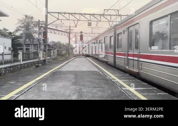 Commuter train departing from a station platform during sunset ...