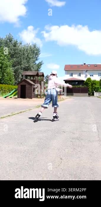 Young preteen girl inline skating fast on asphalt village road under ...