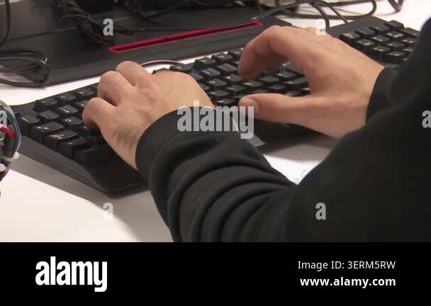 Close up view of a man's hands typing quickly on a computer keyboard ...